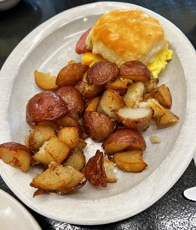 These home fries aren't just cooked, they're transformed – crispy-edged, perfectly seasoned potato chunks escorting a magnificent breakfast sandwich to greatness.