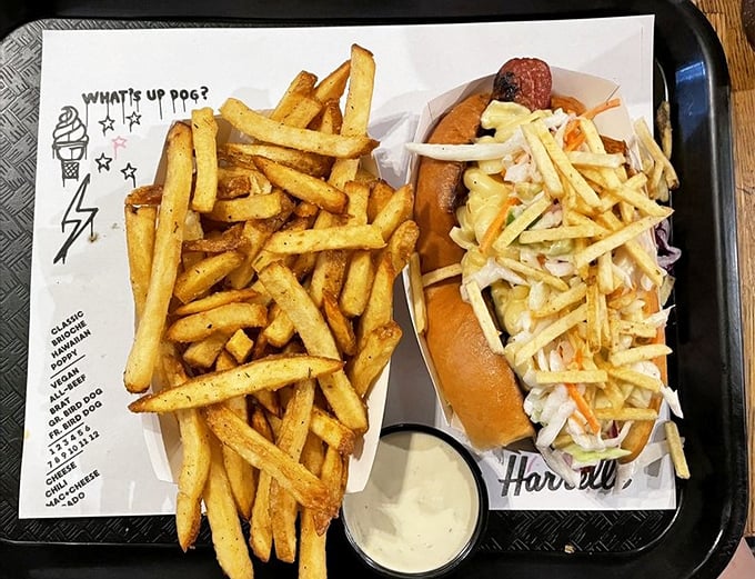 A Carolina Dog with slaw alongside golden fries and house sauce – proof that sometimes the best things in life come in paper boats.