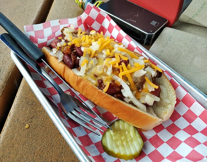 The chili cheese dog arrives like a beautiful mess, demanding both your admiration and a strategy for how to actually eat it.