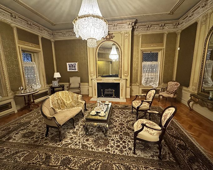 The Ladies Reception Room exudes Gilded Age elegance with its crystal chandelier and ornate fireplace—just waiting for someone in a corset to make an entrance.