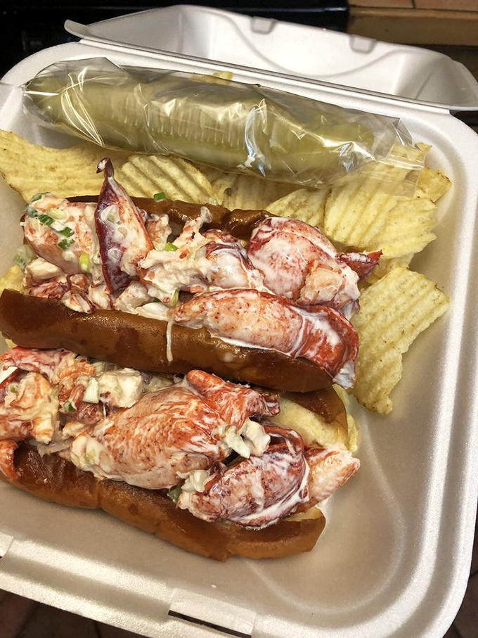 The lobster roll arrives like a seafood celebration—chunks of sweet meat barely contained by a perfectly toasted bun, with chips standing guard.