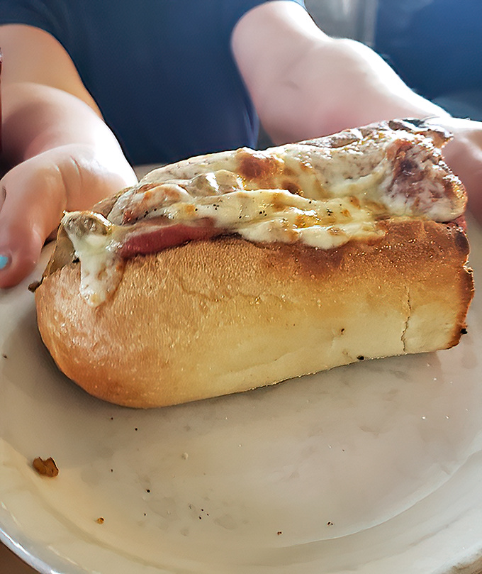 That's not just melted cheese you're looking at—it's a lava flow of dairy goodness threatening to erupt from a perfectly toasted submarine of carb-loaded bliss.