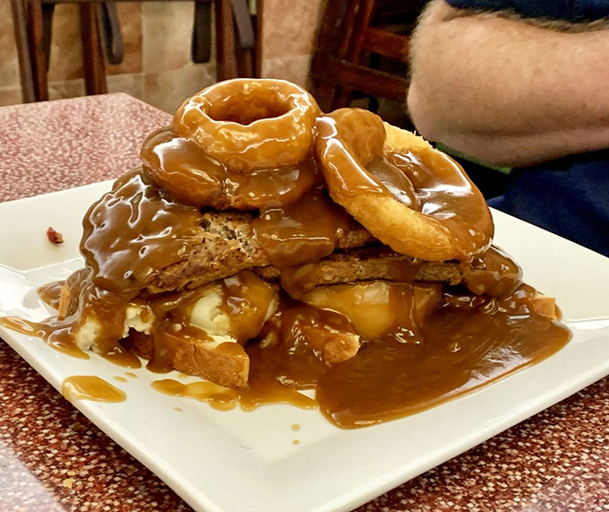Behold the Tower of Power—donuts and French toast stacked higher than your weekend expectations, drowning gloriously in caramel sauce.