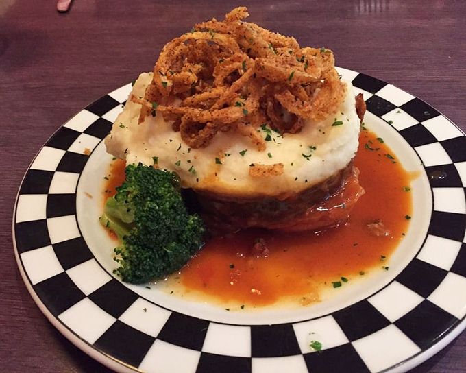 Meatloaf reimagined: topped with crispy onion straws and sitting on a throne of mashed potatoes. Grandma would be jealous—and impressed.