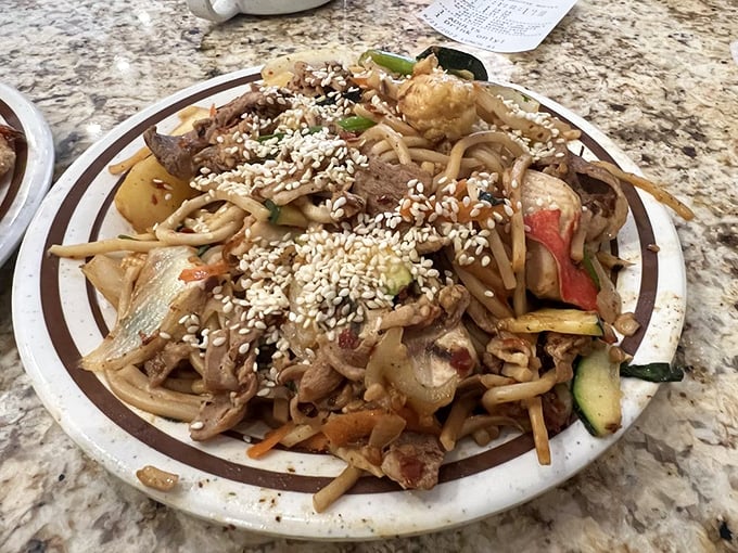 This isn't just noodles—it's a canvas of flavors where sesame seeds rain down like delicious confetti on a celebration of textures and tastes.