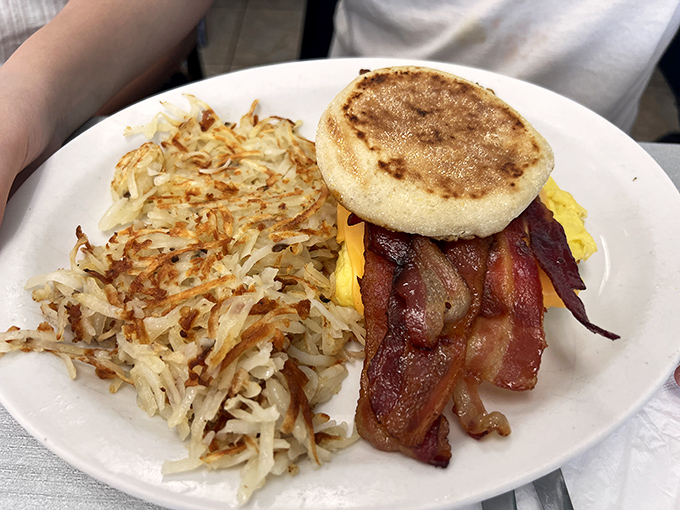 Breakfast architecture at its finest – crispy hash browns, perfectly cooked bacon, and a golden English muffin creating the holy trinity of morning satisfaction.