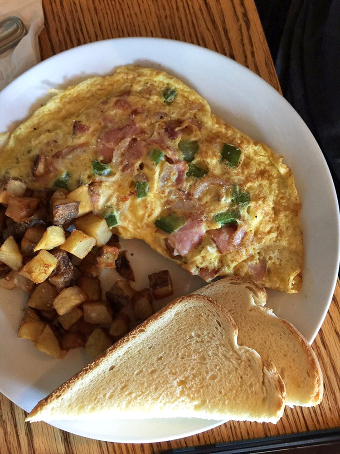 Breakfast perfection doesn't exi—wait, it does! This fluffy omelet studded with ham and veggies alongside crispy home fries makes mornings worth facing.