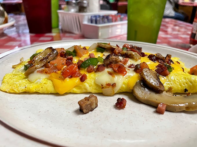 This isn't just an omelet—it's an architectural marvel of perfectly folded eggs cradling a treasure trove of mushrooms, peppers, and cheese that stretches with each bite.