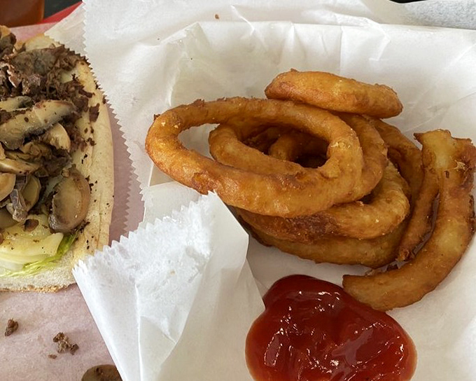 Golden onion rings with that perfect crunch factor – the supporting actor that sometimes steals the show from the cheesesteak star.v