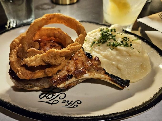 That pork chop isn't just dinner, it's architecture—towering over creamy potatoes with crispy onion rings as its crown. Savory skyscraper.