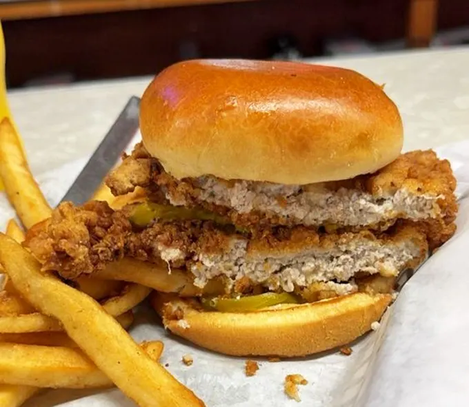 Indiana's beloved pork tenderloin sandwich—where the meat heroically extends beyond the bun's borders like it's trying to escape, but you'll catch every delicious bite.