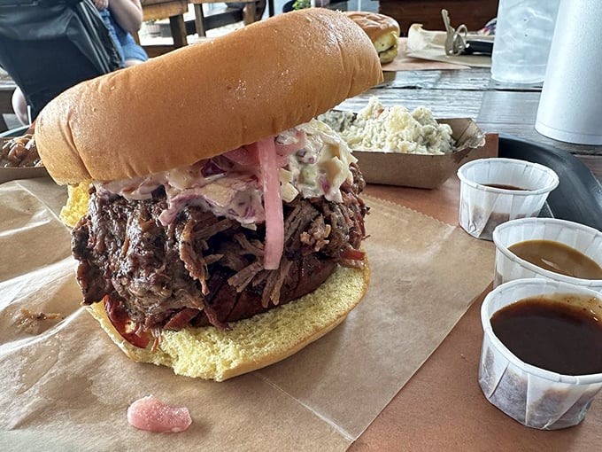 This isn't just a sandwich; it's an architectural marvel of pulled pork, slaw, and sauce that requires both hands and zero shame.