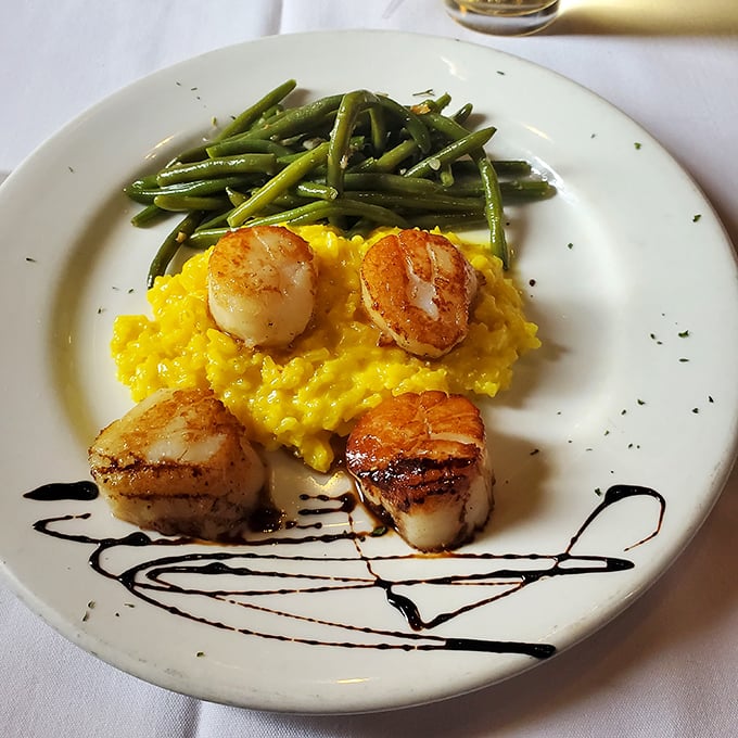 Seared scallops perched atop sunshine-yellow risotto like culinary royalty. The artistic balsamic drizzle isn't just for show – it's the perfect acidic counterpoint.