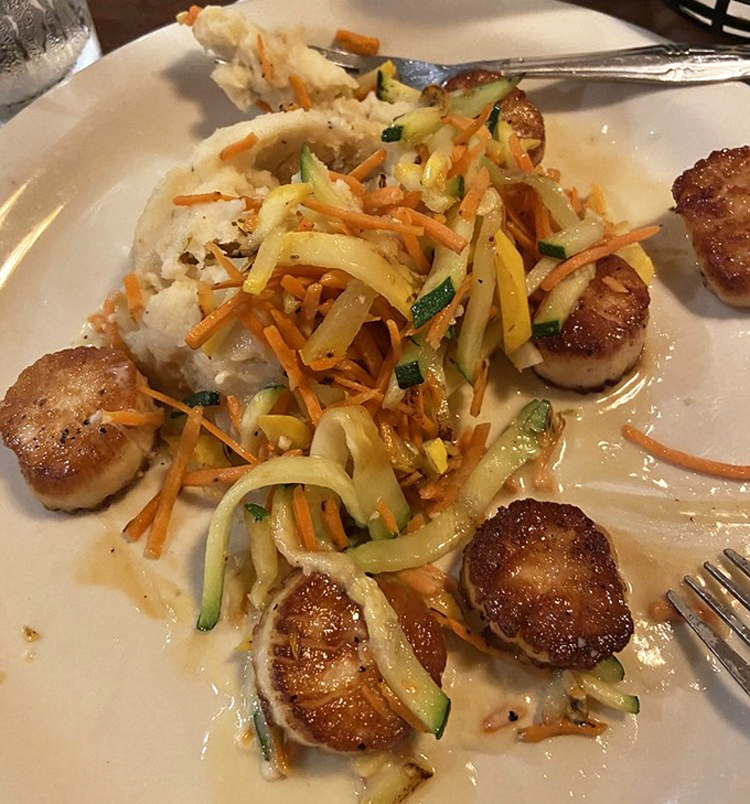 Perfectly seared scallops nestled alongside julienned vegetables and creamy mashed potatoes—seafood that tastes like it should cost twice as much.
