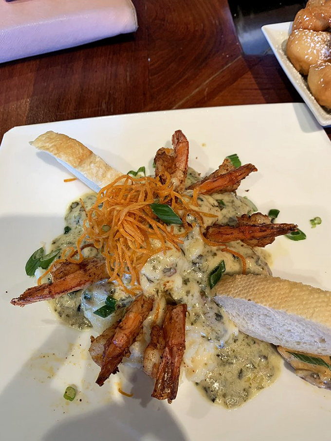 The Grits a Ya Ya arrives like a crown jewel—spiced shrimp standing at attention over creamy grits, with crispy garnish adding the perfect textural counterpoint.