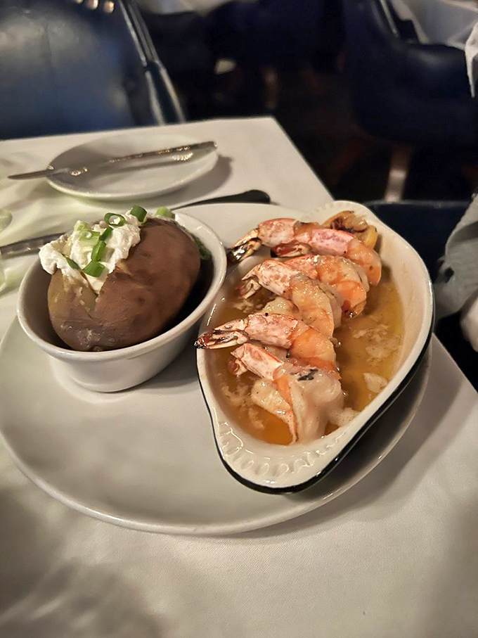 Plump shrimp swimming in butter alongside a loaded baked potato – the kind of surf and turf pairing that makes cardiologists wince and diners smile.