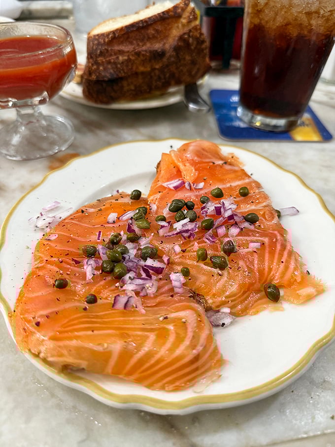 Salmon sashimi adorned with capers and red onion – a silky, coral-colored canvas painted with simple ingredients that somehow create a masterpiece.