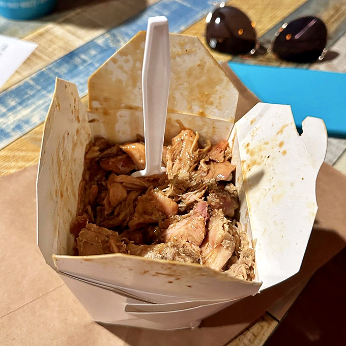 Pulled pork that's been smoked to perfection, nestled in a takeout container like buried treasure waiting to be discovered by your eager fork.