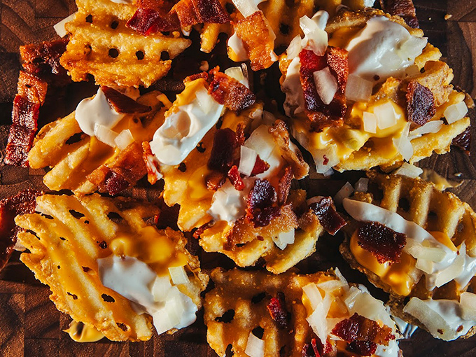Waffle fries elevated to art form with bacon, cheese, and ranch – the holy trinity of comfort food that makes vegetables seem pointless.
