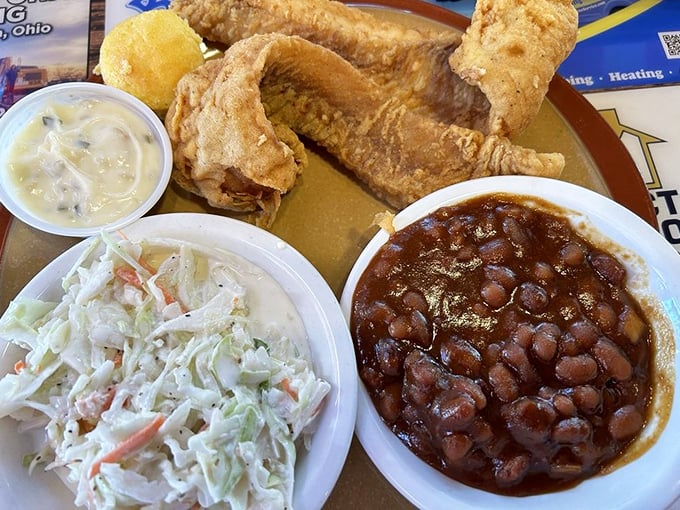Golden fried walleye with creamy coleslaw and baked beans—the holy trinity of Midwestern comfort that makes you feel instantly at home.