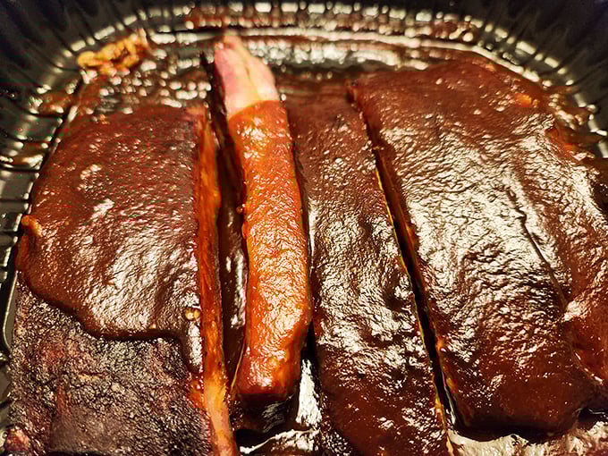 These ribs aren't just glazed – they're wearing a mahogany lacquer that would make fine furniture jealous, with smoke rings that tell tales of patience.