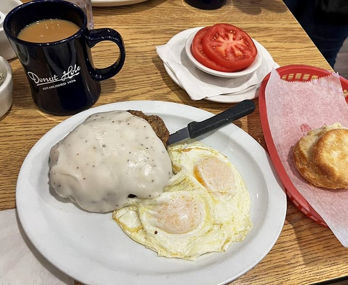 Country gravy cascades over chicken fried steak like a warm Southern blanket, paired with sunny-side eggs that practically wink at you.