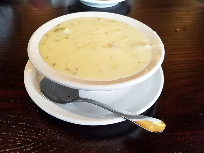 A bowl of creamy clam chowder that whispers, "Cancel your plans for the afternoon—this moment deserves your full attention."