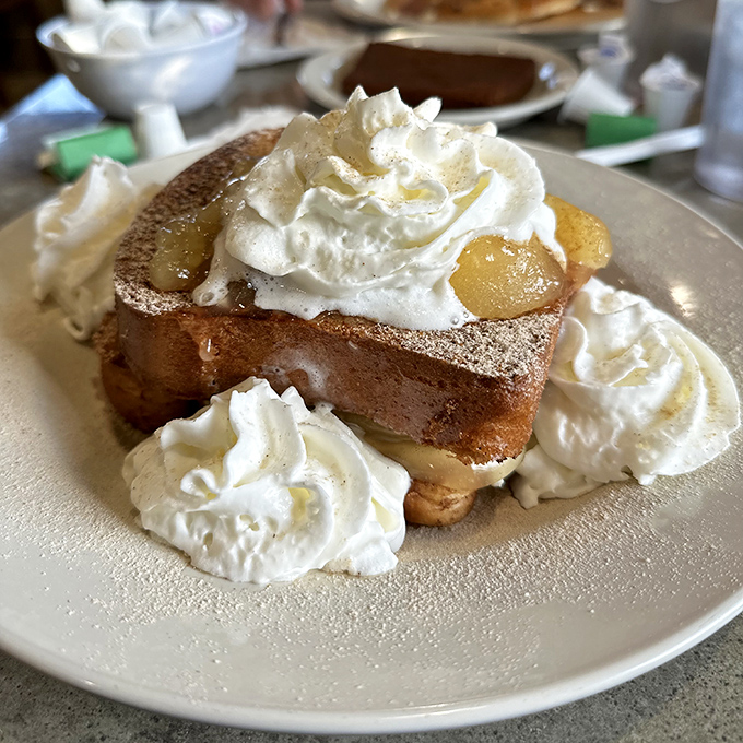 French toast that's having an identity crisis as dessert. With whipped cream islands floating in a sea of sweet syrup—breakfast nirvana achieved.