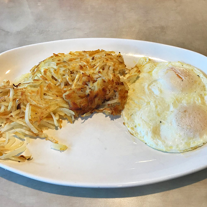 The holy trinity of breakfast perfection—crispy-edged hash browns, sunny-side eggs, and a plate that knows its purpose in life.