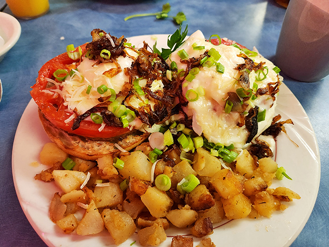 Eggs Benedict with a side of home fries that look like they've been introduced to heat with proper respect and admiration. The green onions add both color and swagger.