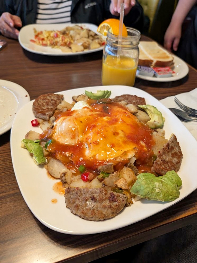 This isn't just breakfast – it's edible artwork. Ranchero sauce cascades over eggs while avocado slices add creamy contrast to a symphony of flavors.