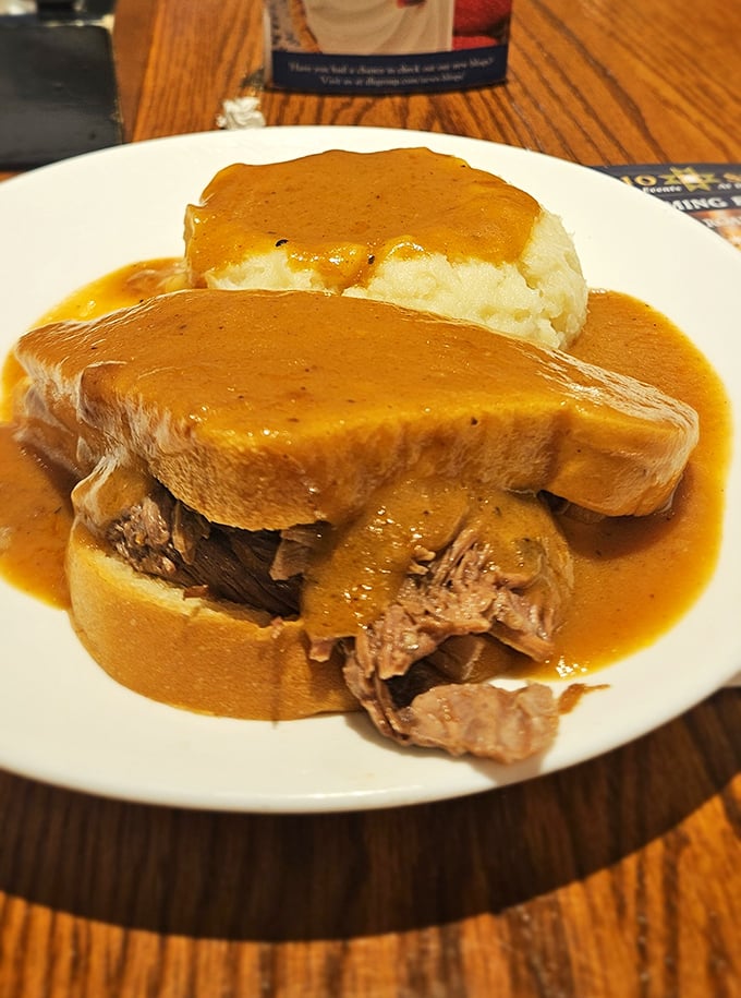 The legendary pot roast sandwich—tender beef surrendering to gravity between bread slices, swimming in gravy that could make cardboard taste like a delicacy.
