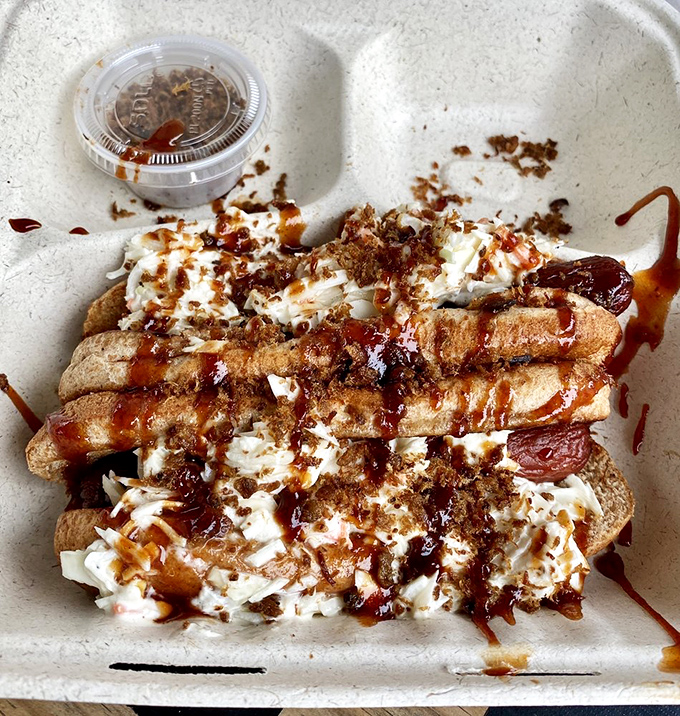 Not your average hot dog experience—this smoke-kissed creation topped with slaw and sauce might just ruin ordinary hot dogs for you forever.