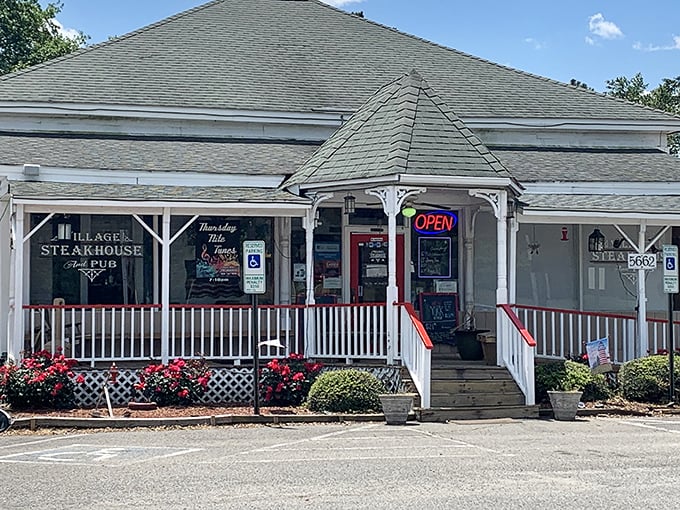 The Village Steakhouse looks like Grandma's house—if Grandma were secretly a steak wizard hiding behind white picket charm.