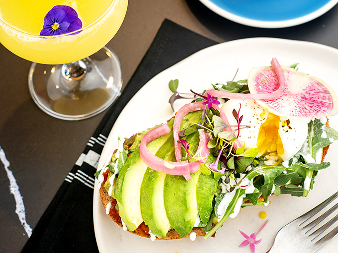 Avocado toast gets the royal treatment with perfectly fanned slices, watermelon radish, and edible flowers—Instagram's favorite breakfast dressed for the red carpet.