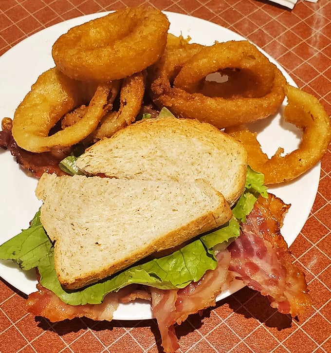 A BLT that doesn't mess around, featuring bacon so perfectly crisp it shatters like glass in a action movie, paired with golden onion rings.