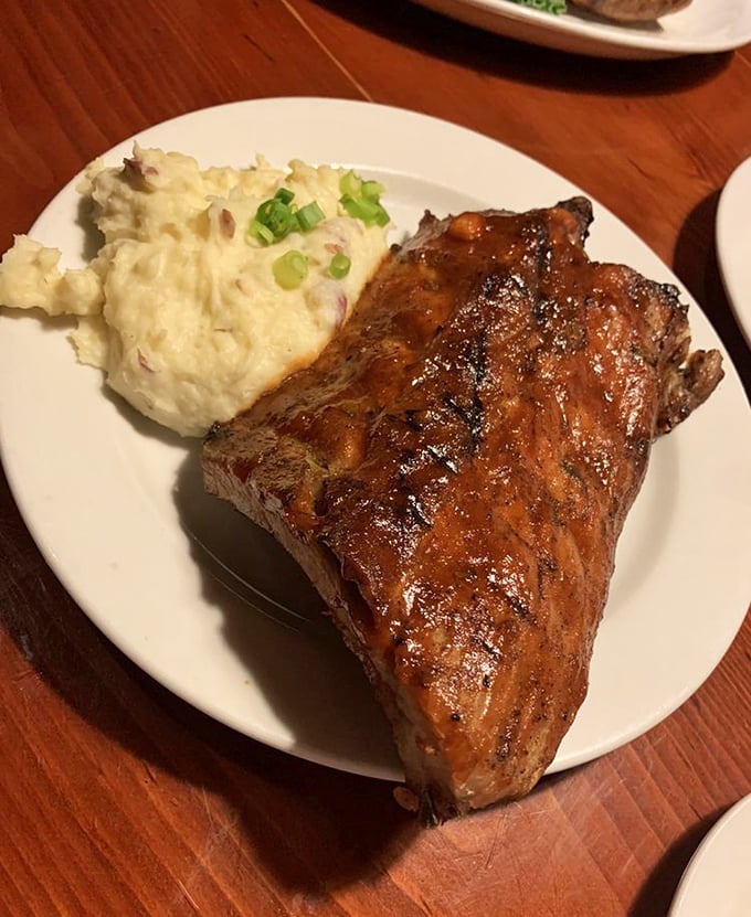 These baby back ribs with their glossy BBQ sheen aren't falling off the bone—they're voluntarily leaping into your mouth while those mashed potatoes stand by as worthy companions.
