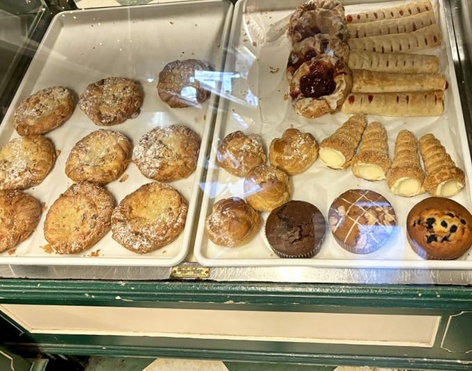 The display case—where willpower goes to die. Each tray offers a different path to happiness, all equally valid and deliciously justified.