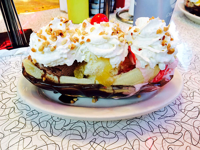 Ice cream architecture at its finest – a towering monument to sweetness where bananas, whipped cream, and nuts come together in perfect harmony.