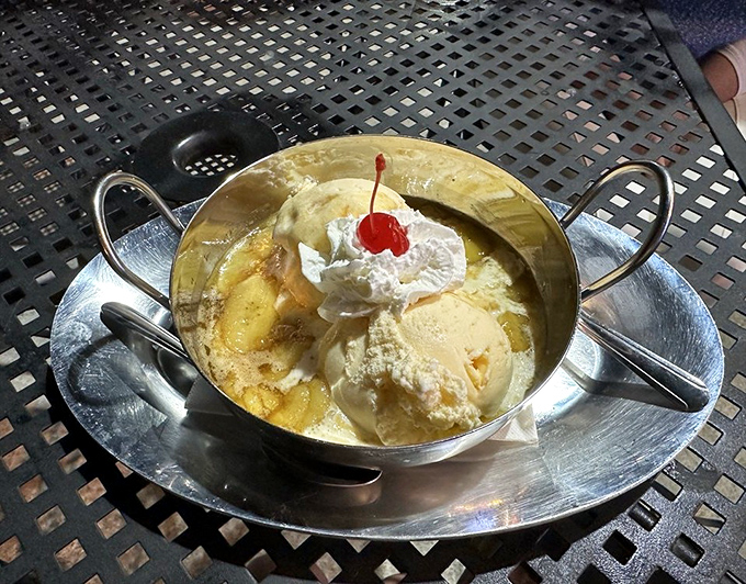 Golden bananas nestled in a silver dish, crowned with vanilla ice cream and whipped cream—proof that simplicity sometimes makes the most profound statement.