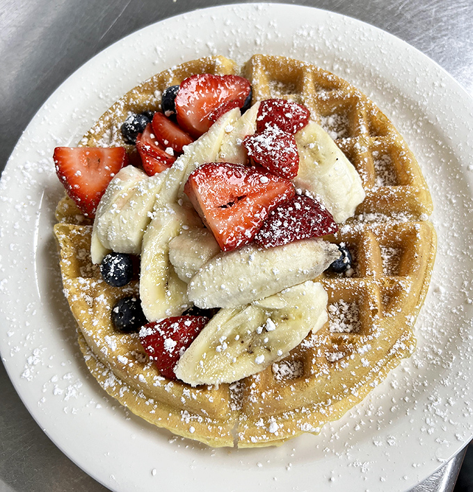A Belgian waffle that serves as both breakfast and art canvas, topped with fresh fruit that almost—almost—makes you feel virtuous about dessert for breakfast.