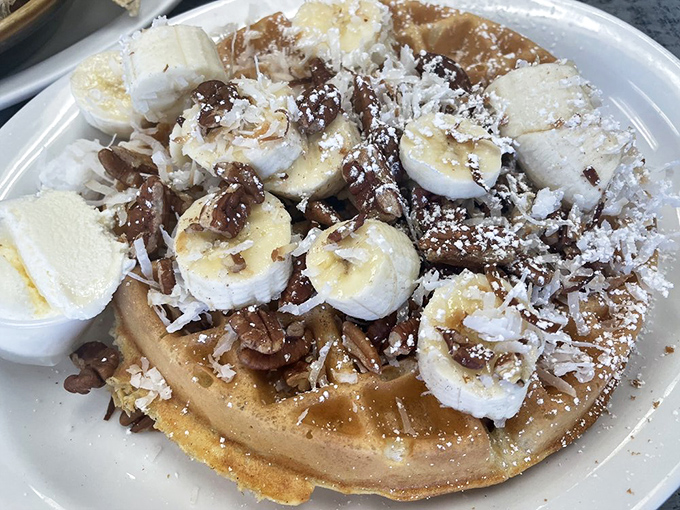 Waffle perfection topped with bananas, pecans, and a dusting of powdered sugar – like a tropical vacation that fits on a fork.