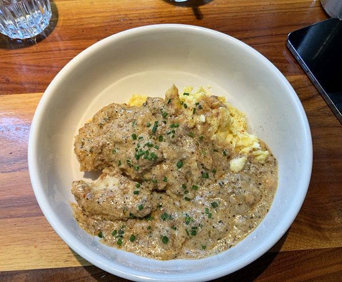 Comfort food reaches its final form in this bowl of biscuits and gravy. The chives aren't just garnish—they're little green confetti celebrating this masterpiece of morning indulgence.