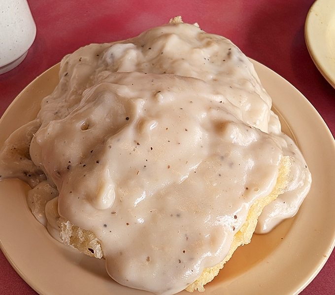 Biscuits and gravy so generous they've disappeared under a creamy avalanche. This isn't a side dish—it's the main event with its own gravitational pull.