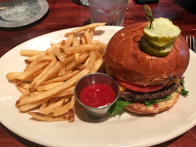 Behold the burger that makes salads question their life choices—a towering creation with crisp pickles standing guard over juicy beef perfection.