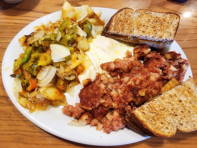 Breakfast alchemy at its finest—crispy home fries, perfectly cooked eggs, and corned beef hash creating a holy trinity of morning deliciousness.