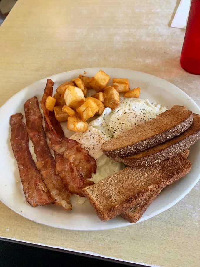 Breakfast perfection in its purest form: crispy bacon, golden toast, eggs, and home fries arranged like the four corners of a delicious universe.
