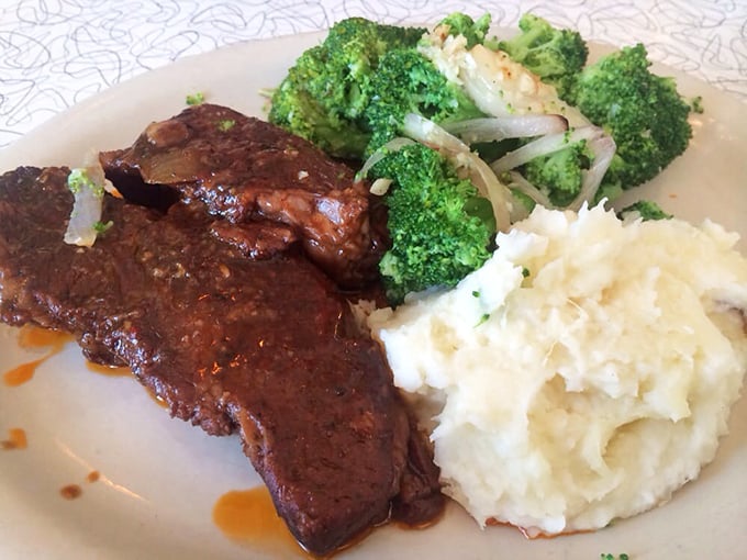 Tender brisket glistening with sauce alongside cloud-like mashed potatoes and vibrant broccoli—a plate that whispers, "Diet? What diet? We're on vacation."