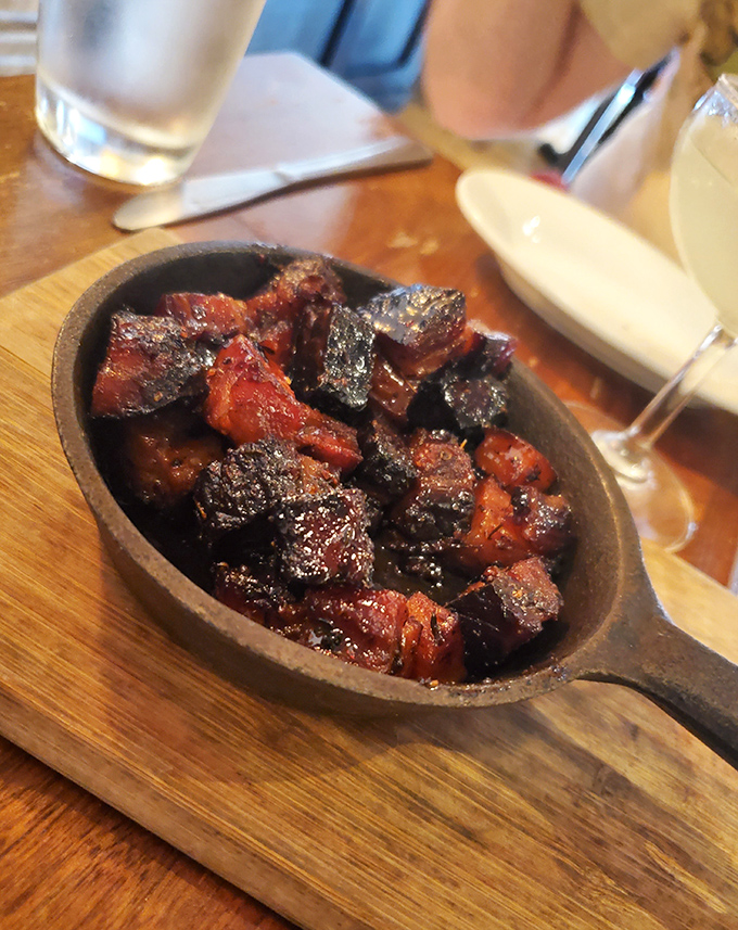 These burnt ends look like they've been kissed by fire and blessed by smoke—glistening, caramelized meat candy in a cast iron skillet.