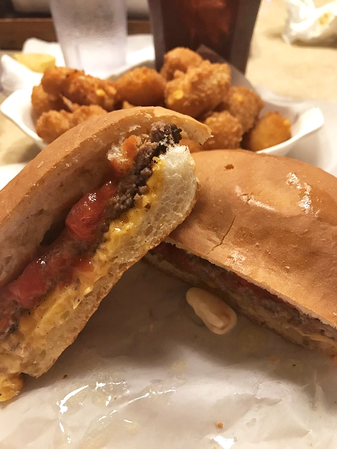 The cross-section reveals the truth: a perfectly charcoal-grilled patty on that distinctive hard roll, with cheese melting just right—burger engineering at its finest.